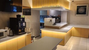 Cozinha moderna com máquina de café, micro-ondas e espaço para café.