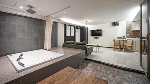 Um banheiro moderno com uma banheira grande, um sofá e uma área de jantar com cadeiras e mesa.
