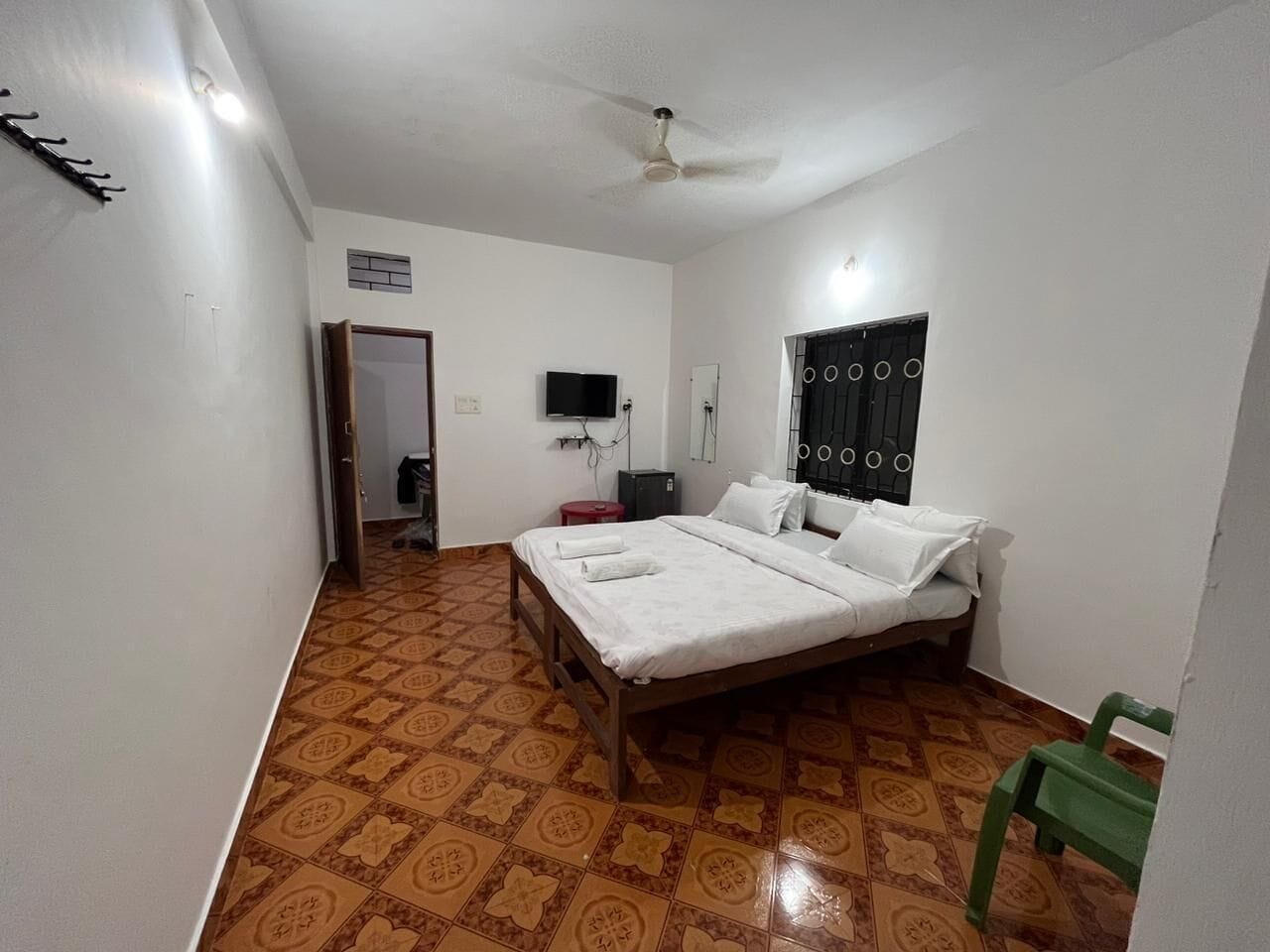 Um quarto pequeno e limpo, com uma cama, televisão e ventoinha no teto.
