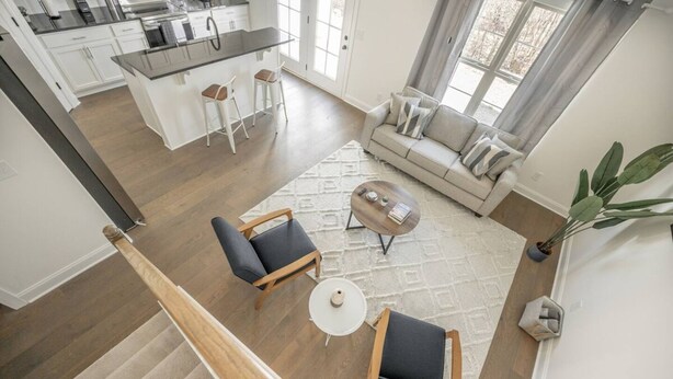 Uma sala de estar moderna com um sofá, duas poltronas, uma mesa de centro e uma escada que leva ao andar superior.