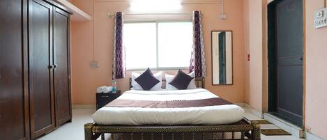 Quarto com cama, guarda-roupa, janela com cortinas e uma porta.