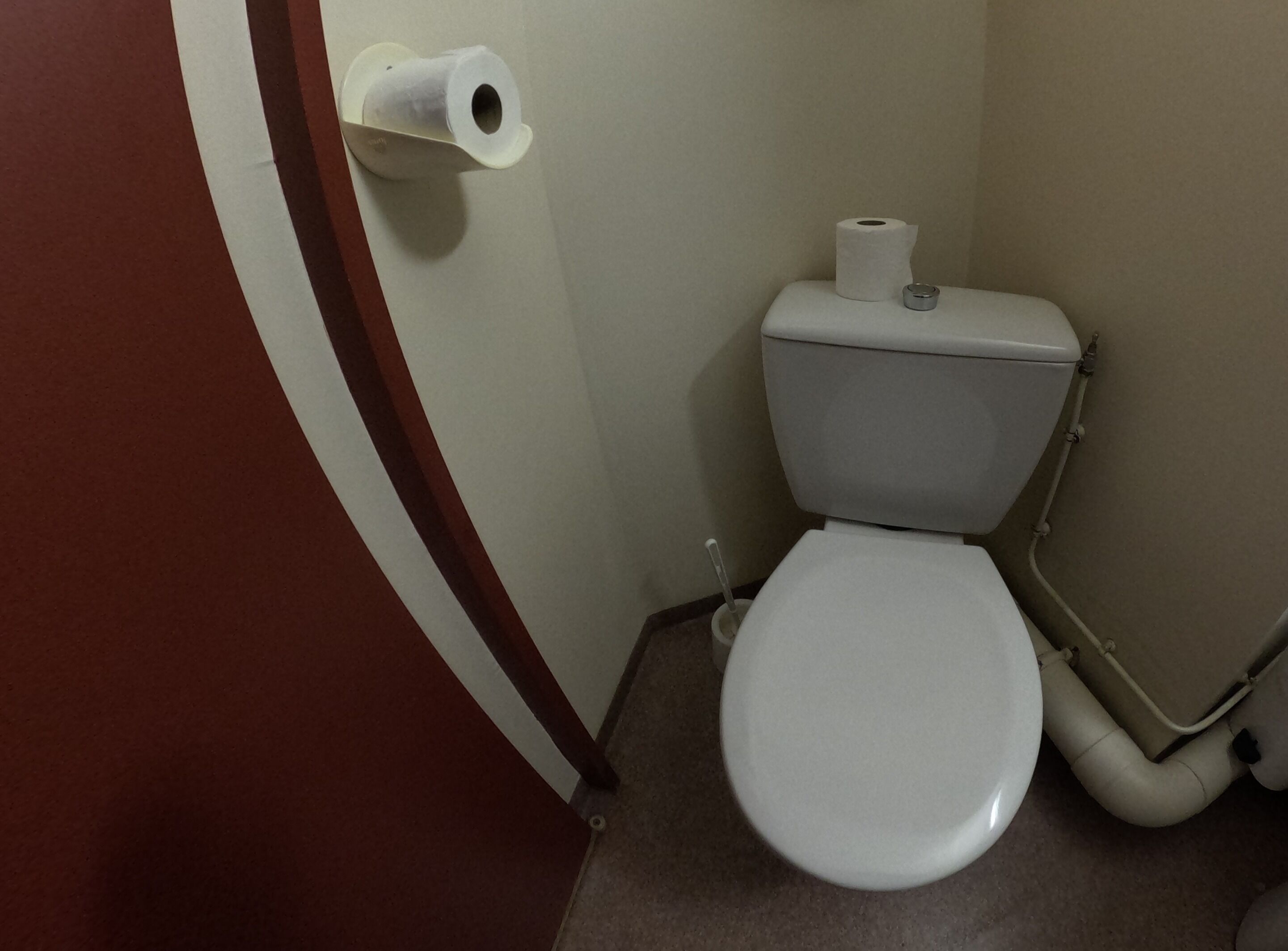 Um banheiro pequeno e compacto com vaso sanitário, suporte para papel higiênico e bidê.