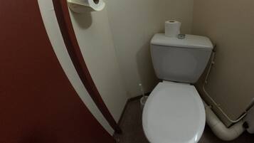 Um banheiro pequeno e compacto com vaso sanitário, suporte para papel higiênico e bidê.