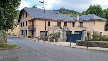 Um edifício de dois andares com fachada de pedra, várias varandas e um portão de entrada.