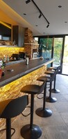Cozinha moderna com bancada de mármore, banquetas de bar e parede com detalhes em pedra.