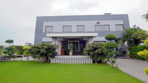 Um edifício moderno de dois andares com telhado plano, entrada central com porta de vidro e pequena varanda.