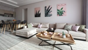 Uma sala de estar moderna com sofá, mesa de centro e cozinha ao fundo.