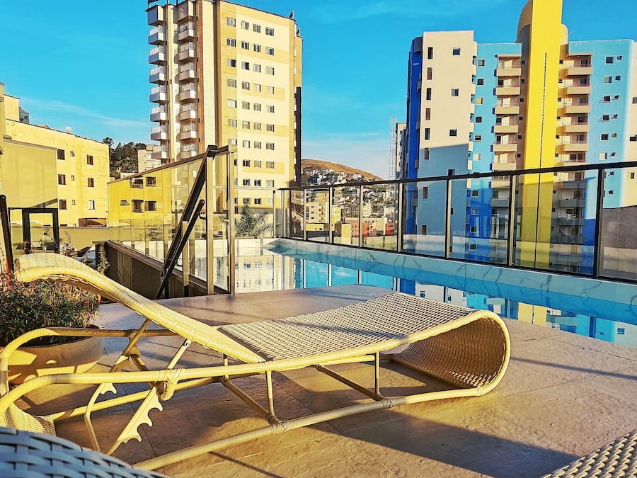 Uma piscina no terraço com espreguiçadeiras e vista para edifícios ao redor.
