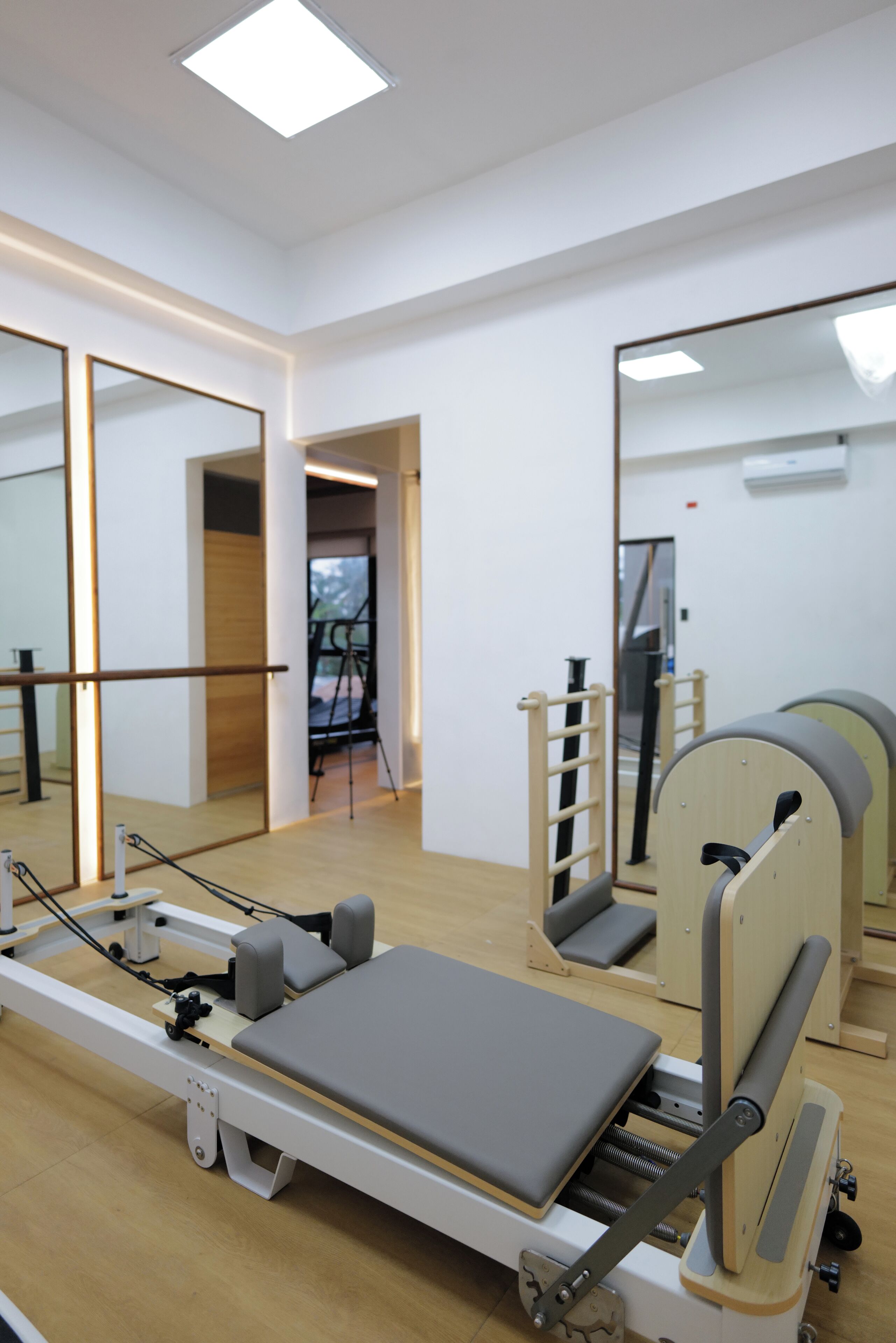 Um ambiente clínico com uma maca de tratamento, equipamentos de exercícios e espelhos.