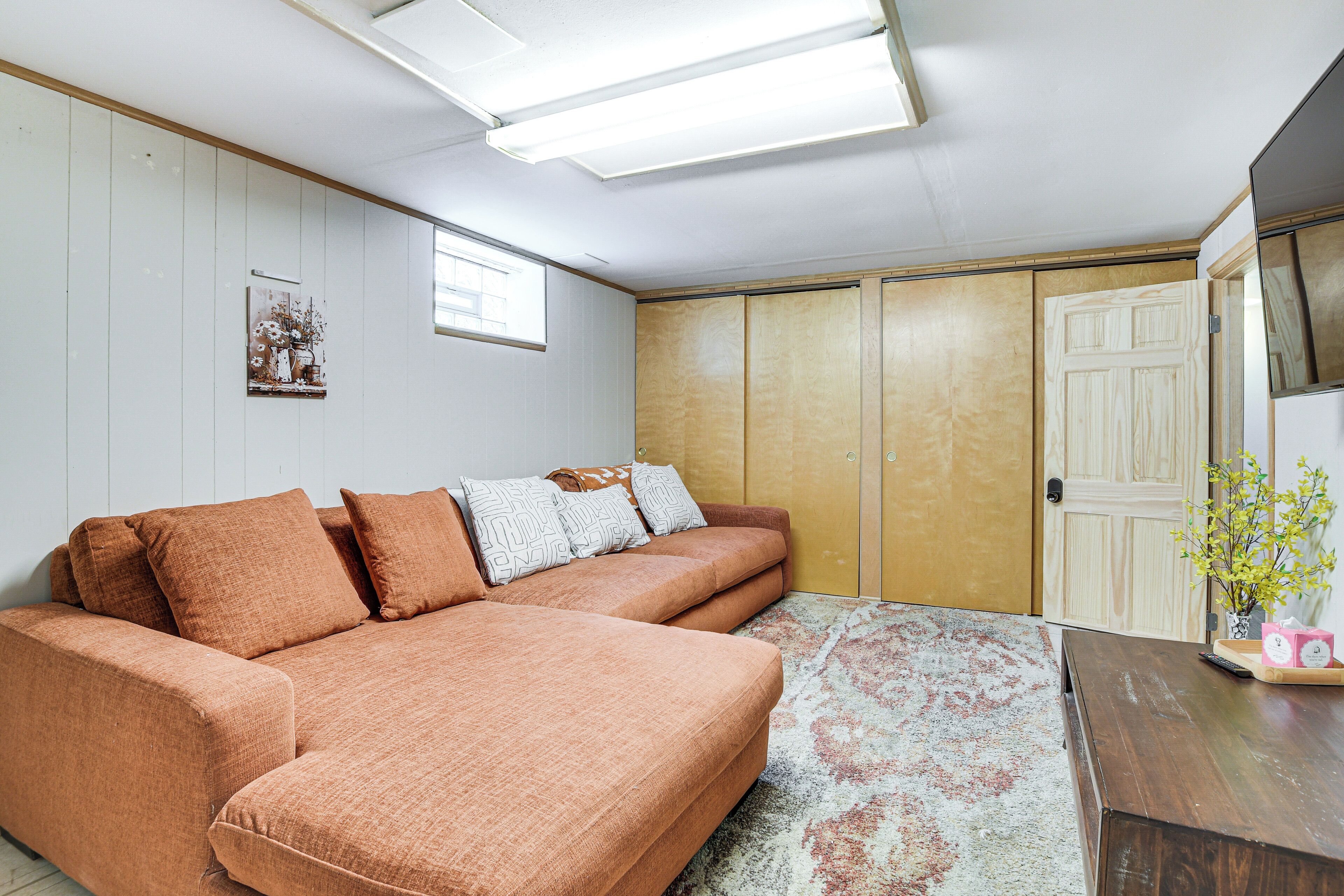 Sala de estar com sofá seccional, aparador de madeira e uma pequena mesa com objetos decorativos.