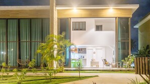 Uma casa moderna de dois andares com cozinha aparente, janelas amplas e área de estar externa.