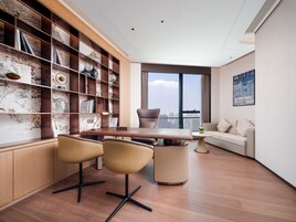Uma sala de estar moderna com uma escrivaninha de madeira, duas cadeiras, um sofá e uma janela grande com vista para a cidade.