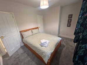 Quarto com cama, porta, luminária e cortina.