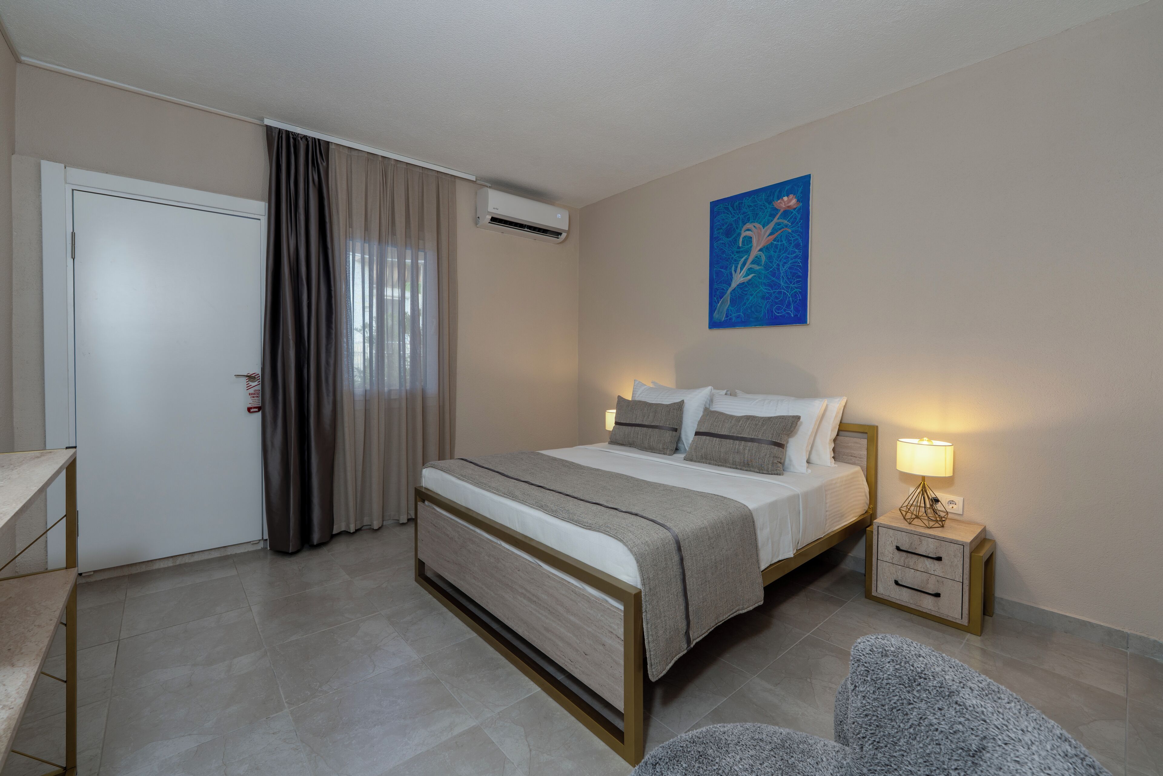 Quarto de hotel com cama, mesas de cabeceira, uma cadeira e um quadro na parede.