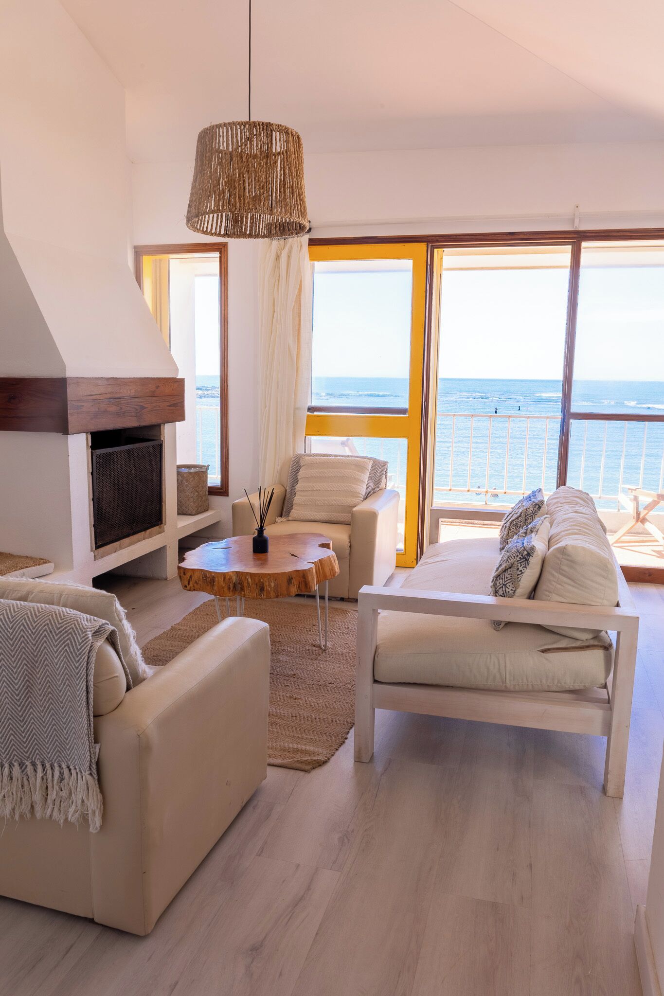 Uma sala de estar moderna com lareira, janelas amplas e vista para o mar.