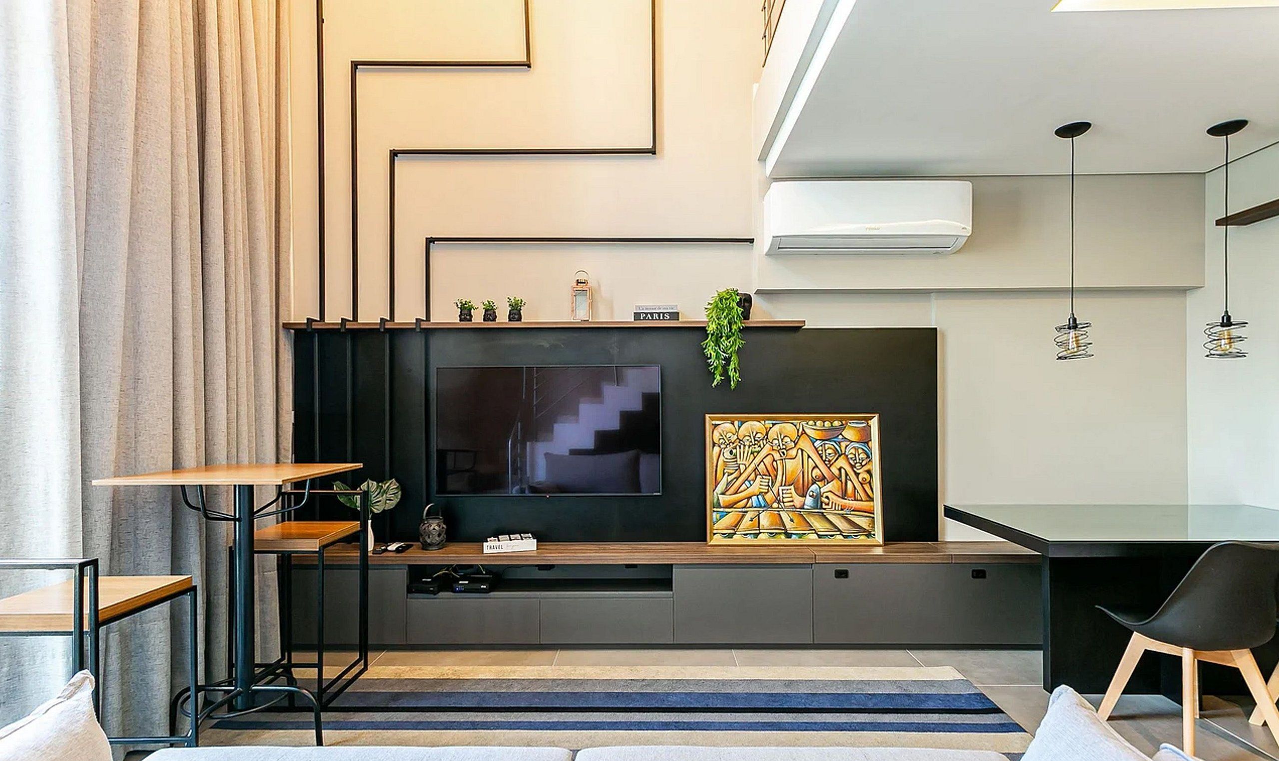 Uma sala de estar moderna com televisão embutida, um quadro decorativo e uma pequena planta na lareira.
