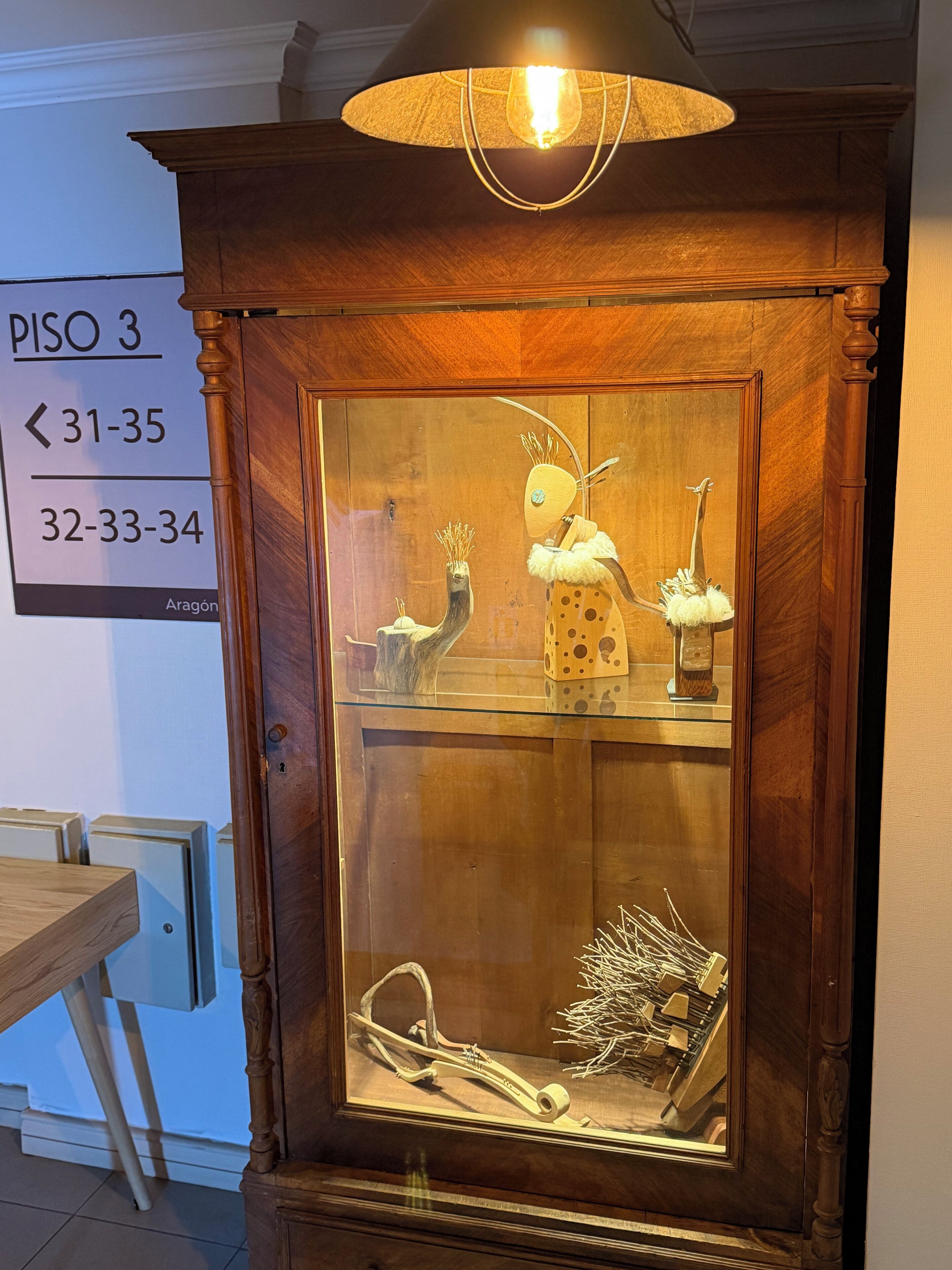 Um armário de madeira com portas de vidro exibindo vários objetos decorativos.