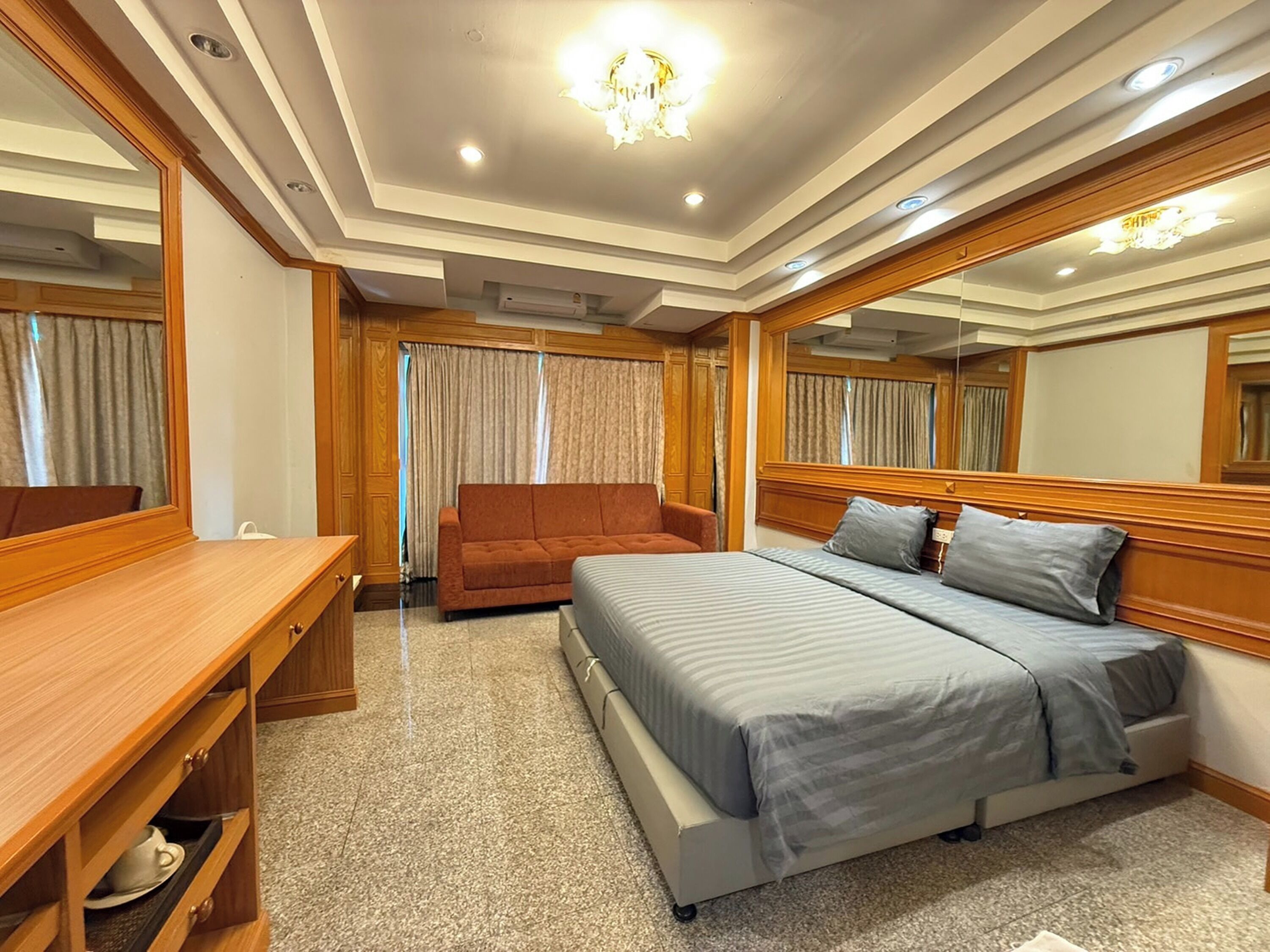 Quarto de hotel com cama grande, escrivaninha de madeira, cadeira e espelho.