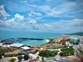 Paisagem costeira com um imponente campanário, uma ponte e um porto de iates.