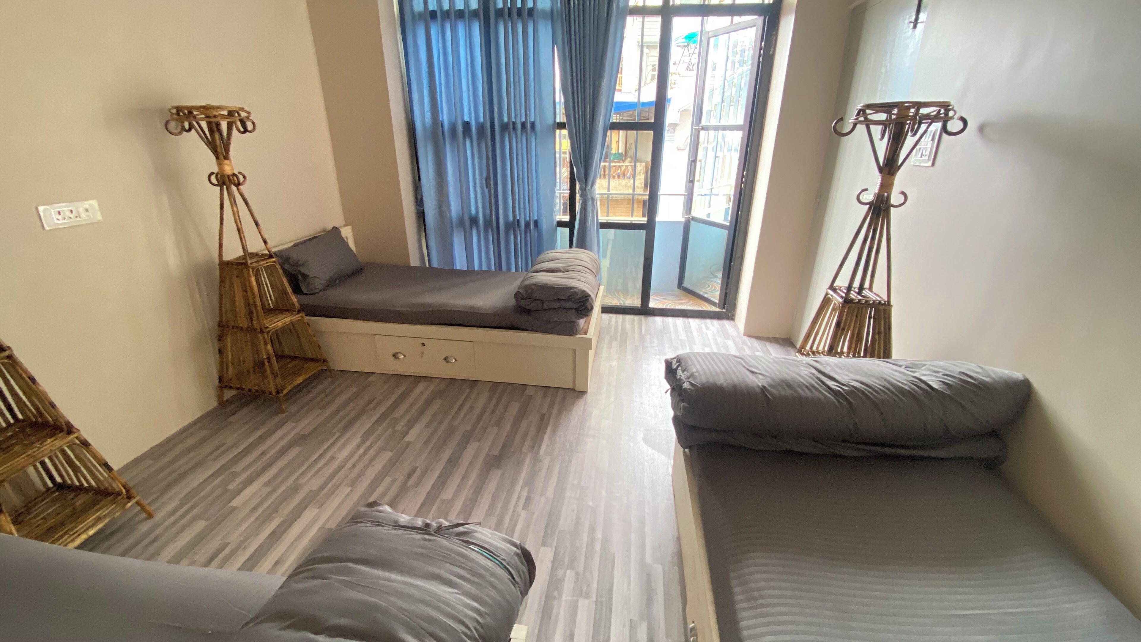 Quarto pequeno e aconchegante com cama, sofá e janela com cortinas.