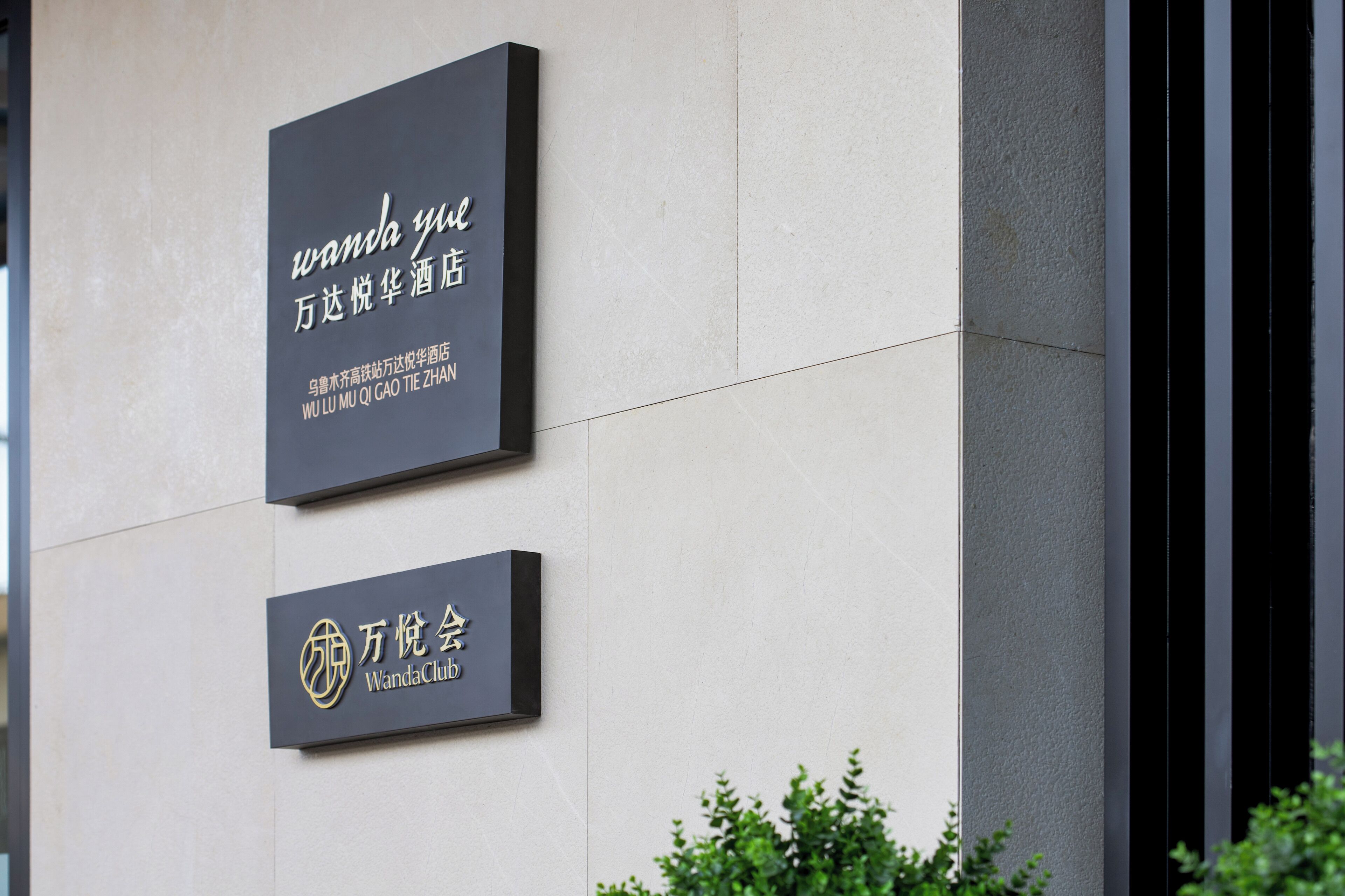Duas placas numa parede de edifício, uma com o nome 'Wanda Yu' e a outra com 'Wanda Club'.