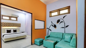 Quarto com cama, sofá azul-turquesa e parede com mural floral.