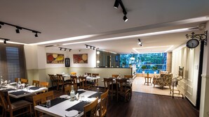 Um restaurante com mesas e cadeiras de madeira, um relógio na parede e vista para o exterior.