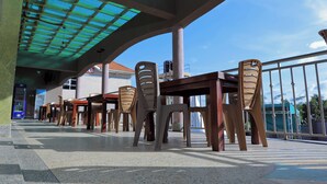Espaço ao ar livre com mesas e cadeiras sob uma cobertura de vidro.
