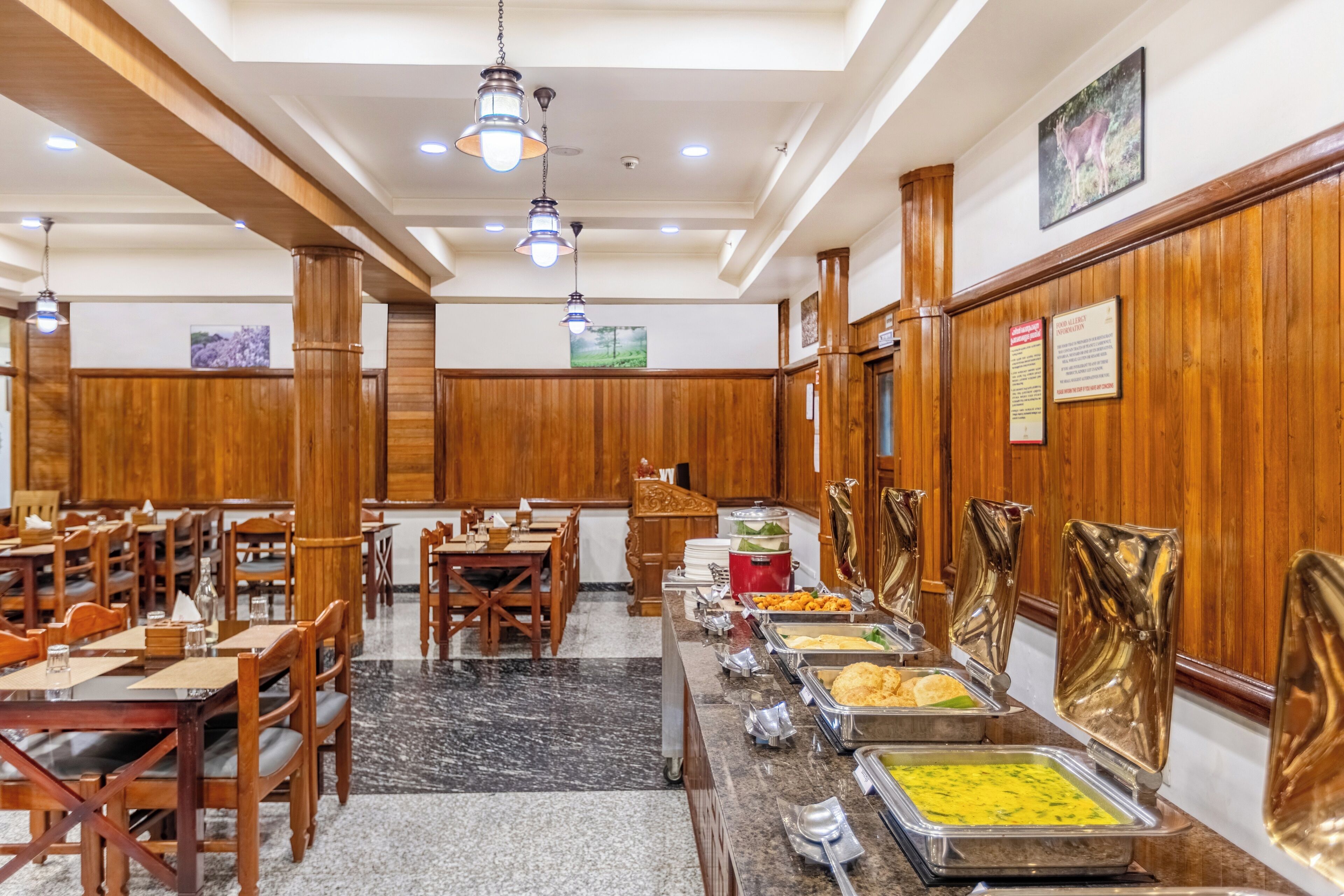 Uma disposição de buffet com várias estações de comida, painéis de madeira e iluminação no teto.