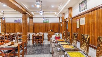 Uma disposição de buffet com várias estações de comida, painéis de madeira e iluminação no teto.