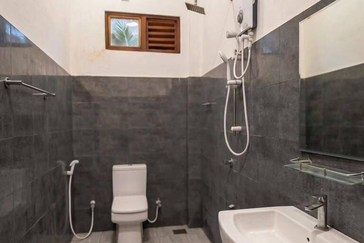 Uma casa de banho com sanita, chuveiro e lavatório.