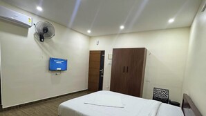 Quarto com cama, guarda-roupa, ventoinha e televisão.