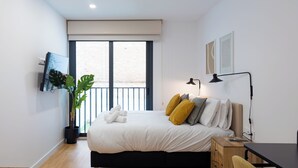 Quarto moderno com cama, mesa de cabeceira, escrivaninha, cadeira e um vaso de planta.