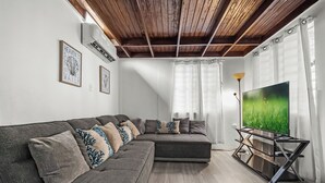 Uma sala de estar moderna com um sofá seccional, uma TV de tela plana em um móvel e um ventilador de teto.