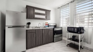 Cozinha moderna com geladeira, fogão, micro-ondas e cafeteira sobre um carrinho.