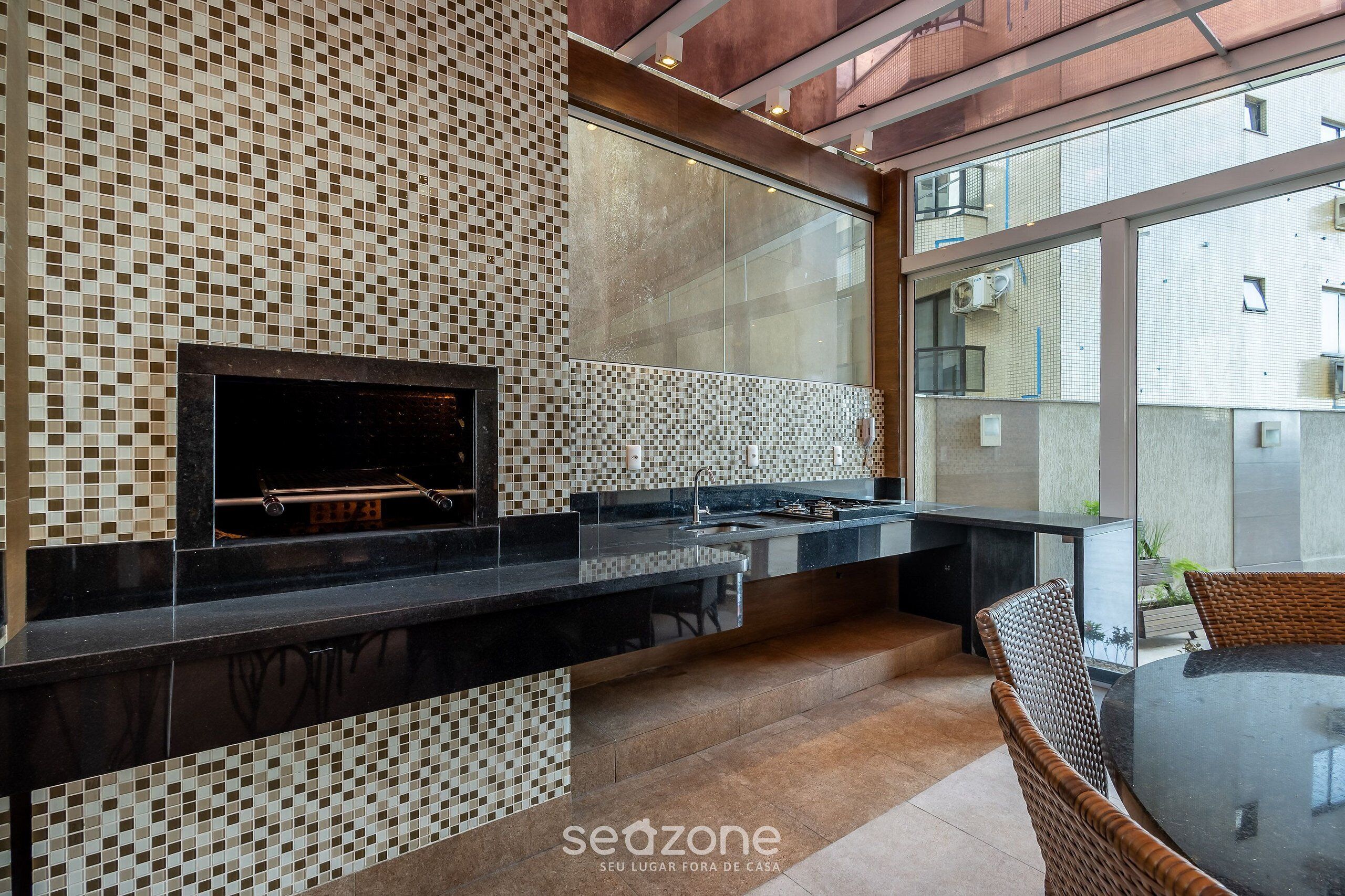 Cozinha moderna com painel de azulejos, forno embutido e área de jantar com cadeiras de vime.