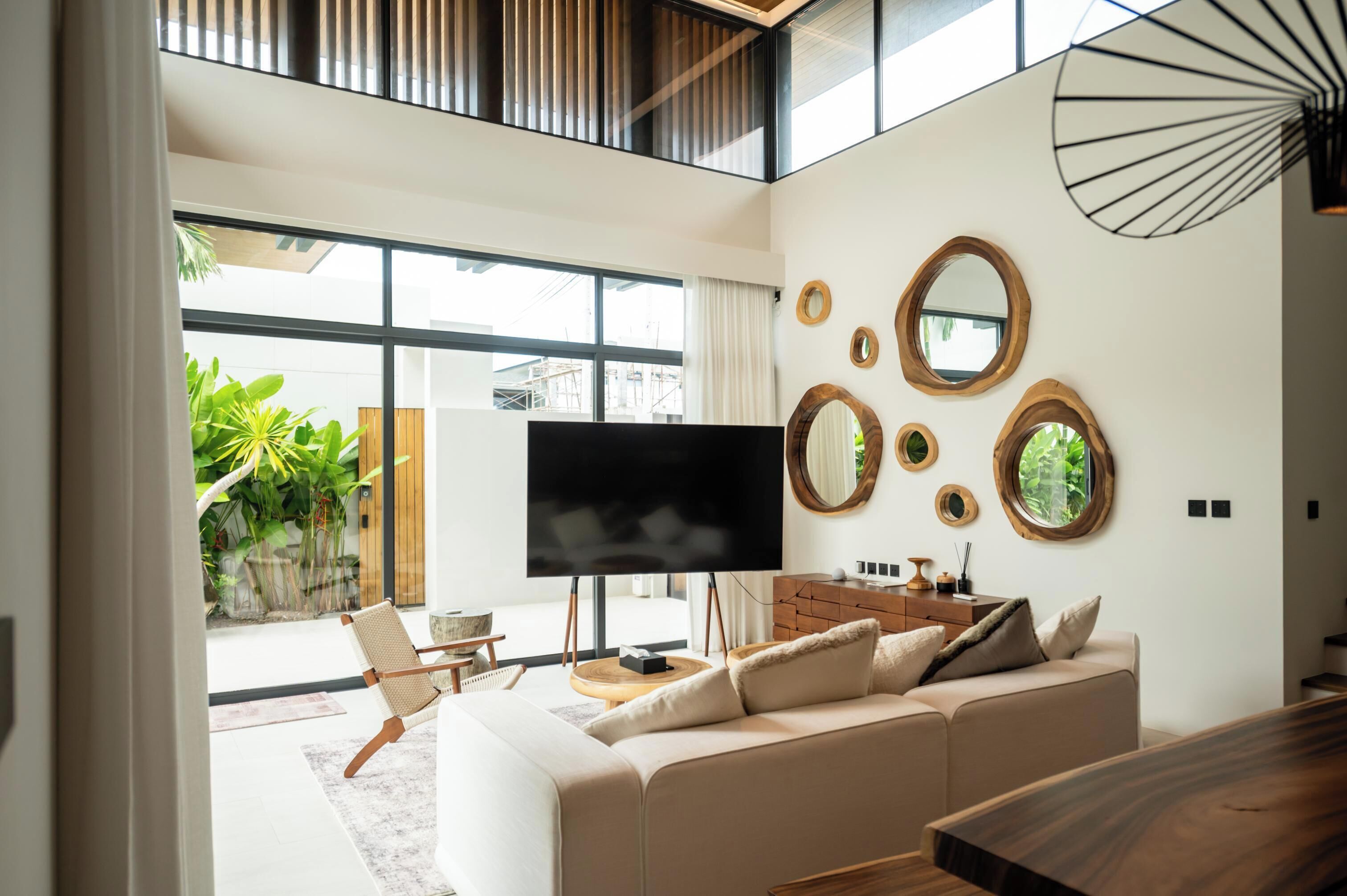 Uma sala de estar moderna com uma televisão grande, um sofá e espelhos decorativos na parede.