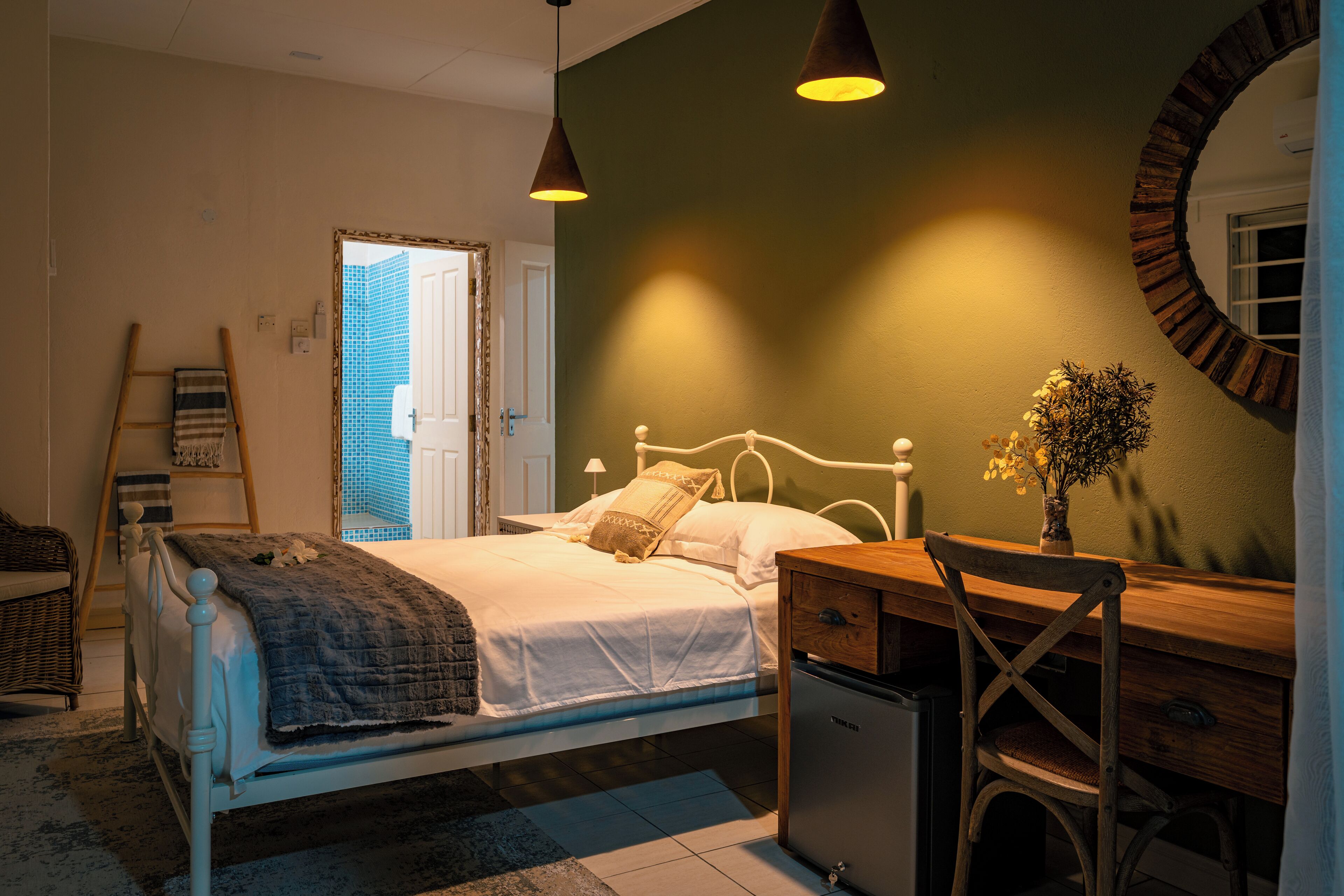 Um quarto com cama, cômoda e escrivaninha.