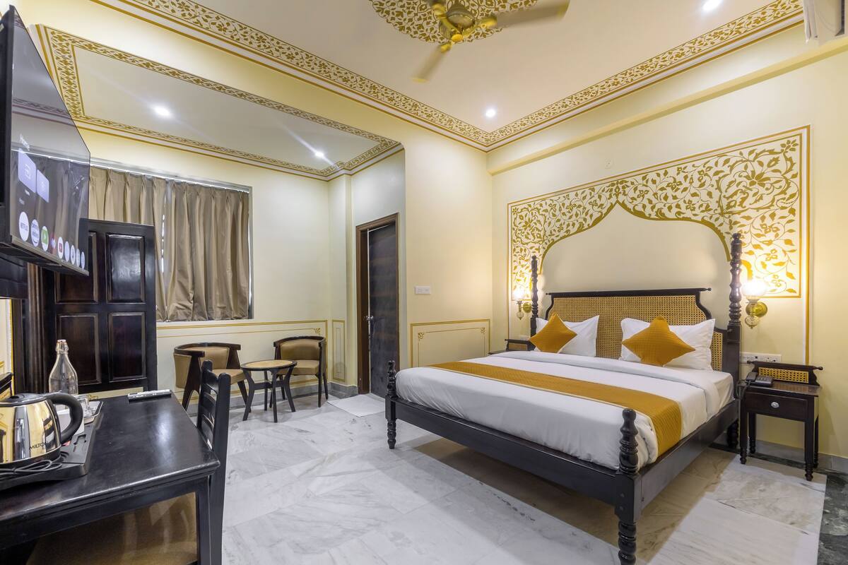 Quarto de hotel bem equipado com uma cama grande, uma mesa com chaleira e uma televisão.