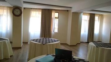 Quarto de hotel com uma mesa redonda, um laptop e um travesseiro azul.