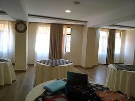 Quarto de hotel com uma mesa redonda, um laptop e um travesseiro azul.