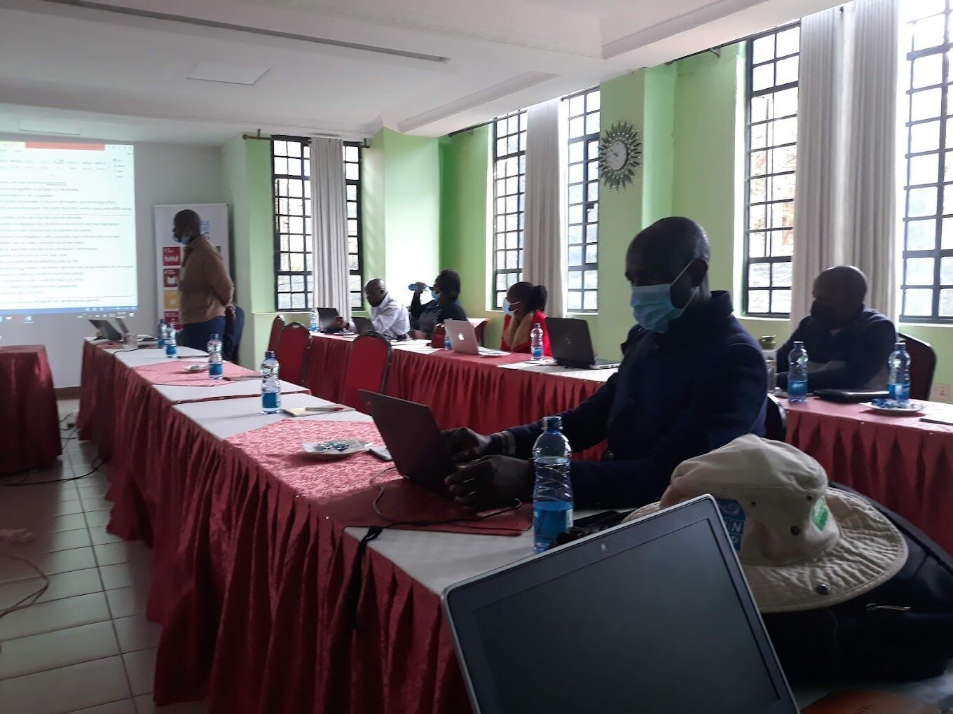 Sala de conferências com mesas, laptops e garrafas de água.