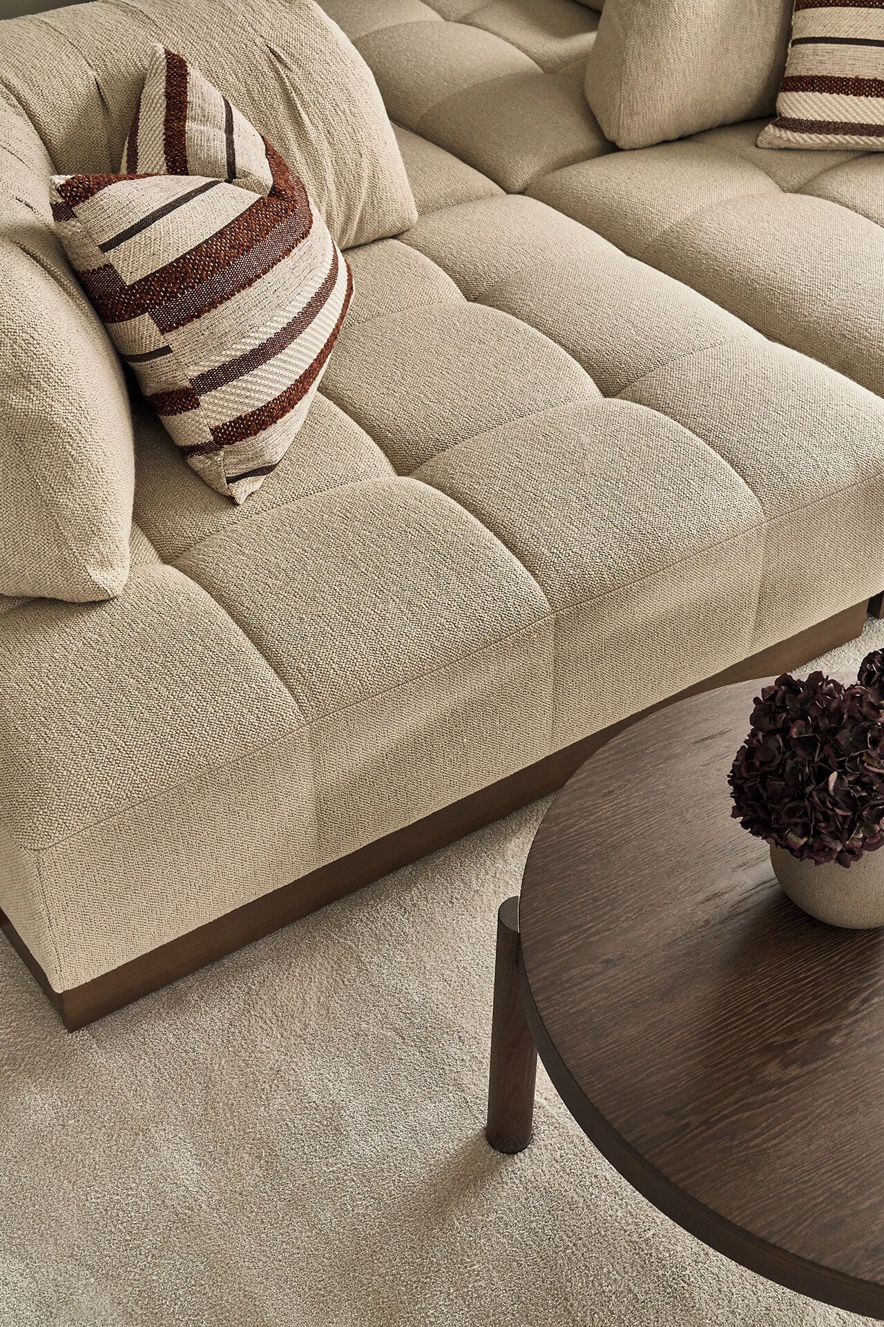 Sofá modular bege com tecido texturizado e almofada listrada.