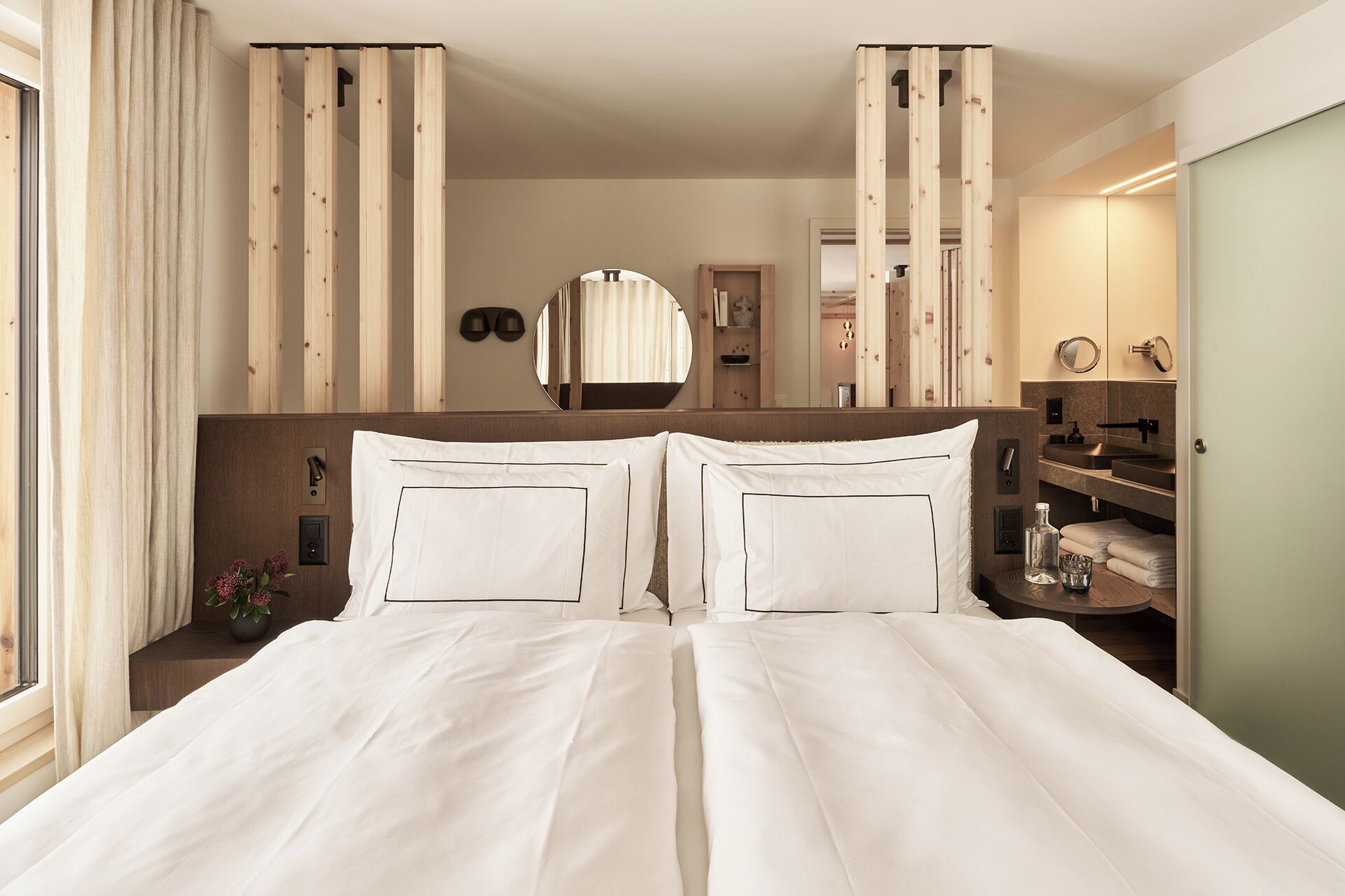 Quarto de hotel com uma cama grande, mesa de cabeceira, espelho e vista para o banheiro.
