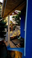 Uma área de estar coberta ao ar livre, com vista para a rua e um edifício ao fundo.