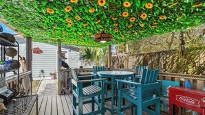 Um deck de madeira com área de estar externa, churrasqueira e cooler da Coca-Cola.