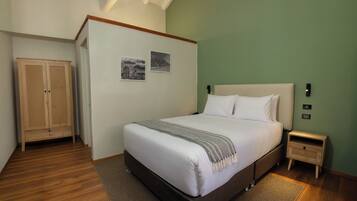 Quarto com cama, mesas de cabeceira, guarda-roupa e dois interruptores de luz na parede.
