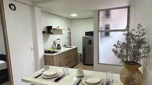 Uma cozinha moderna com ilha central, banquetas brancas, geladeira e micro-ondas.