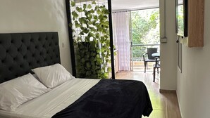 Quarto com cama grande, janela com vista para o exterior e porta deslizante que dá para uma varanda.