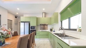 Uma cozinha moderna com armários verdes, bancada de mármore e forno embutido.